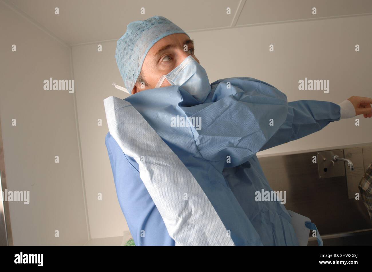 A surgeon prepares for an operation by putting on the appropriate ...