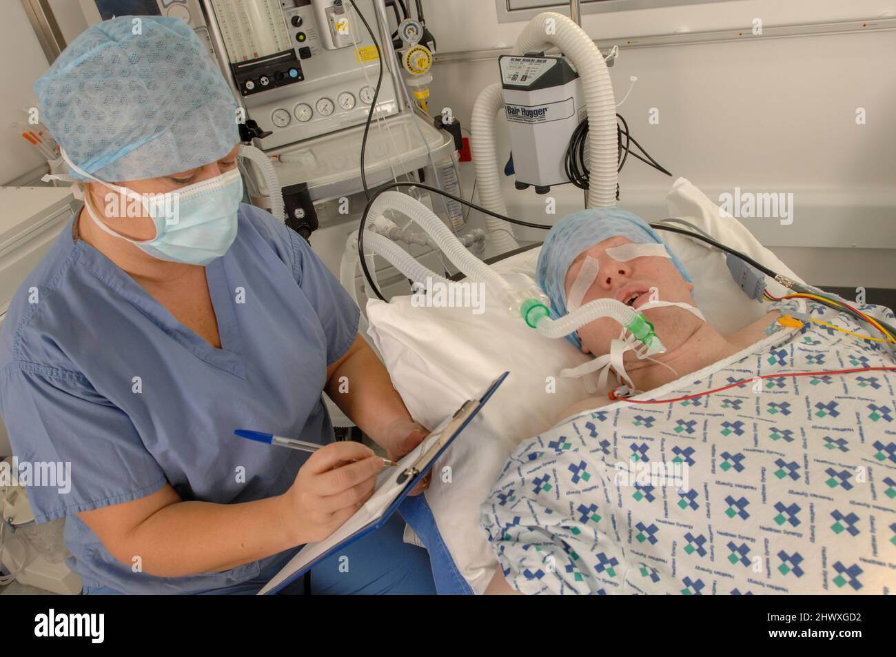 A surgeon's assistant takes notes on a patient and monitors their vital ...
