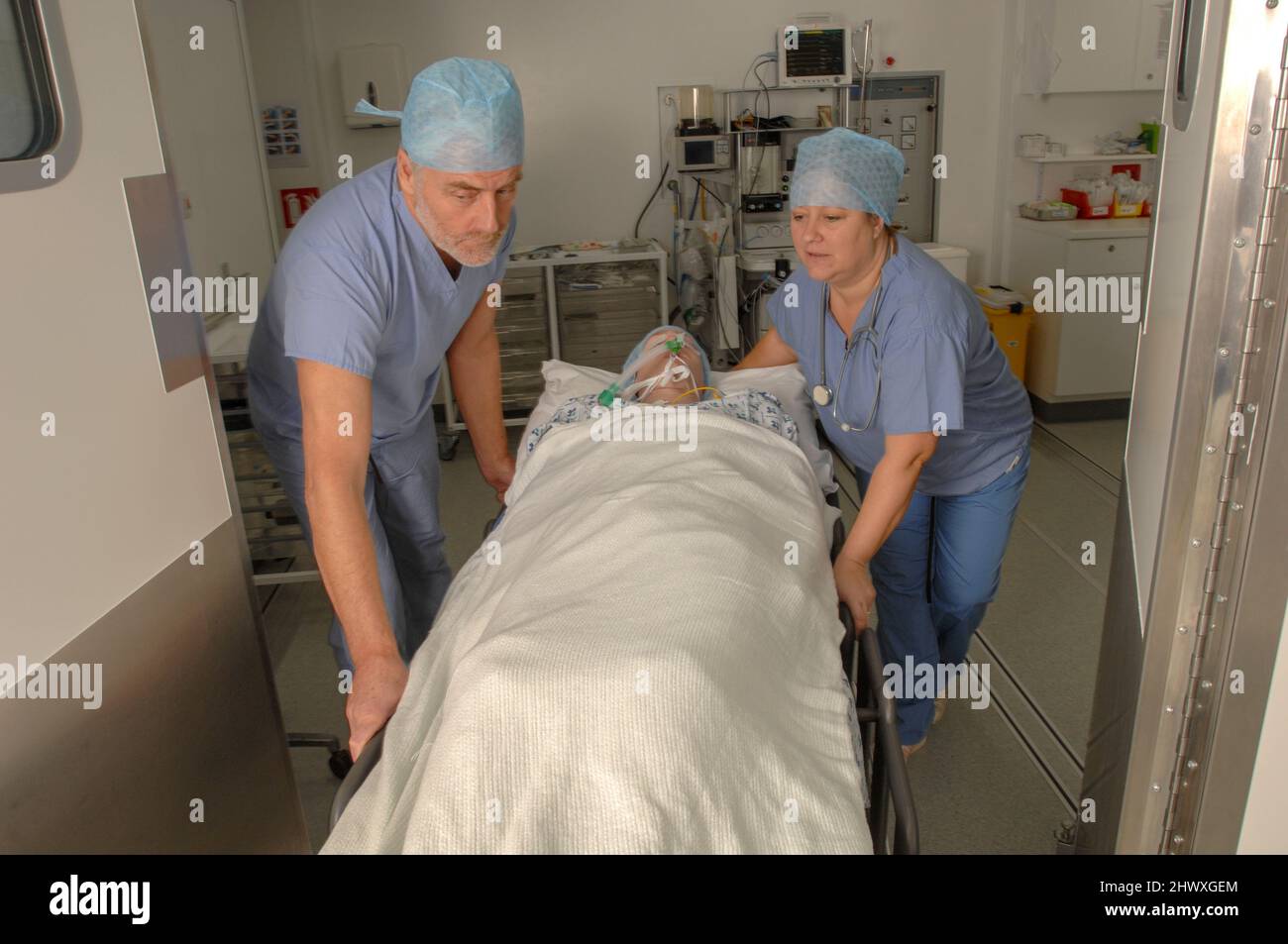 A surgeon and his assistant move a patient to an operating theatre ...