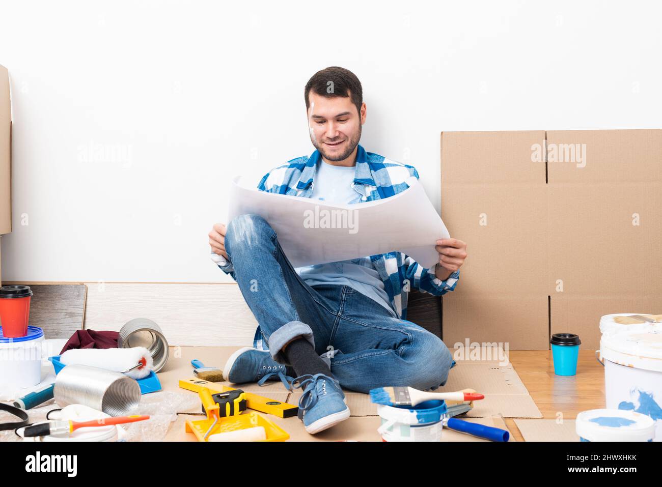 Guy looking at paper blueprint while sitting Stock Photo - Alamy