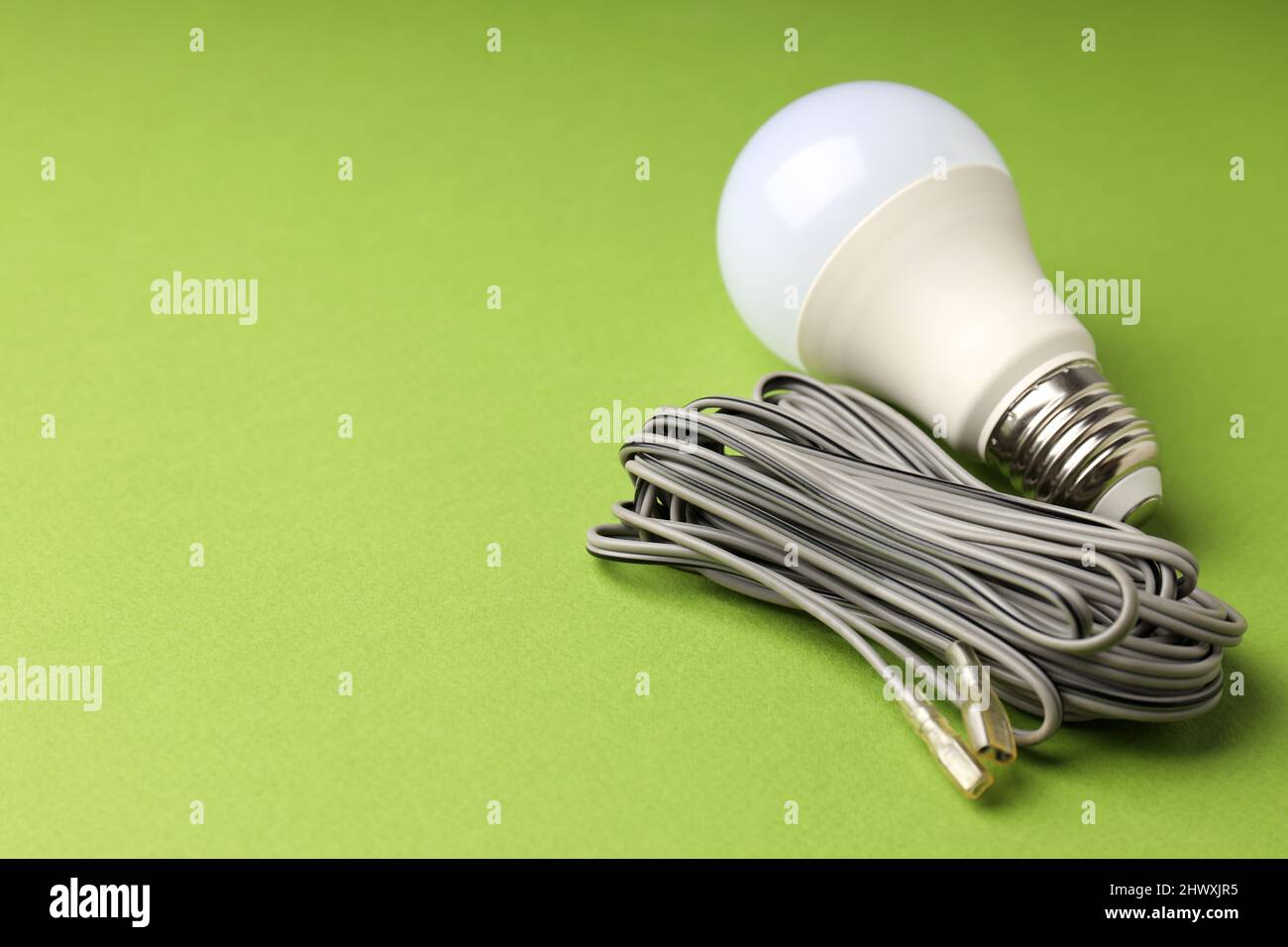 Energy saving bulb and wire on green background Stock Photo - Alamy