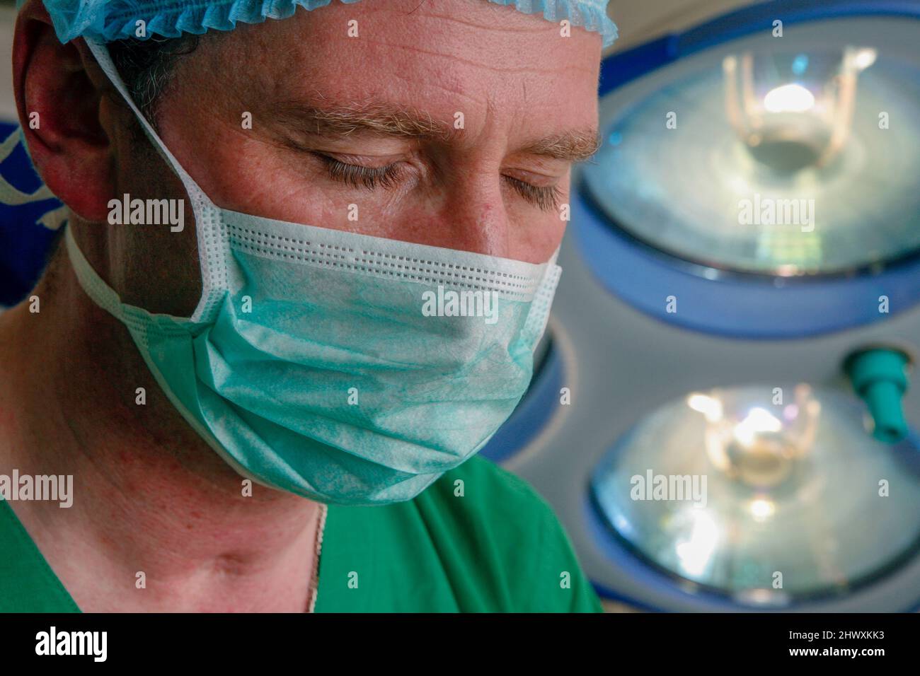 A masked surgeon sleeps unnderneath a surgical light in a operating ...