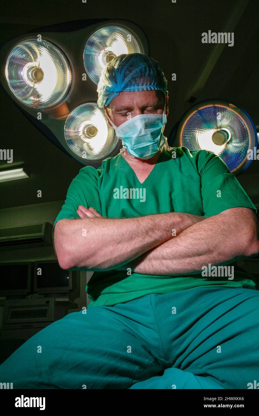 Tired surgeon sits on an operating table with folded arms (MODEL ...