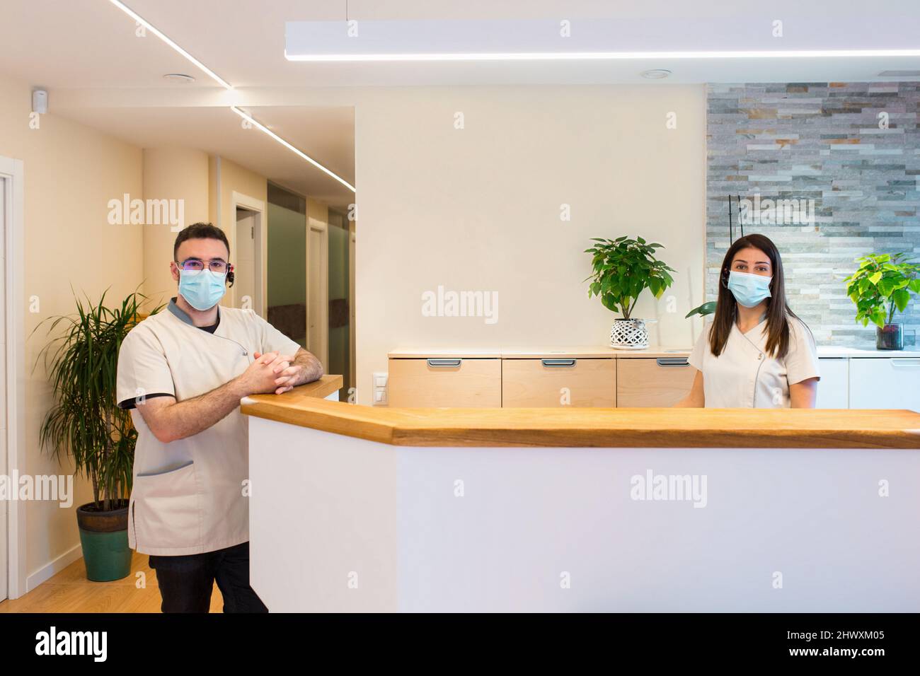 Female and male receptionist looking at the camera while standing at ...