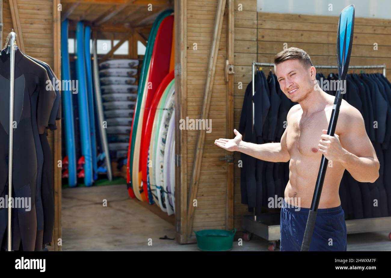 Athletic man standing near hangar with surf equipment Stock Photo - Alamy