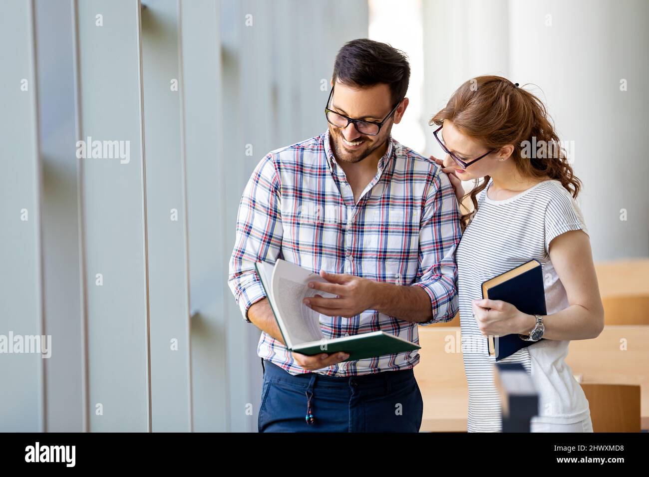 Happy young university students studying with books in library. Group ...