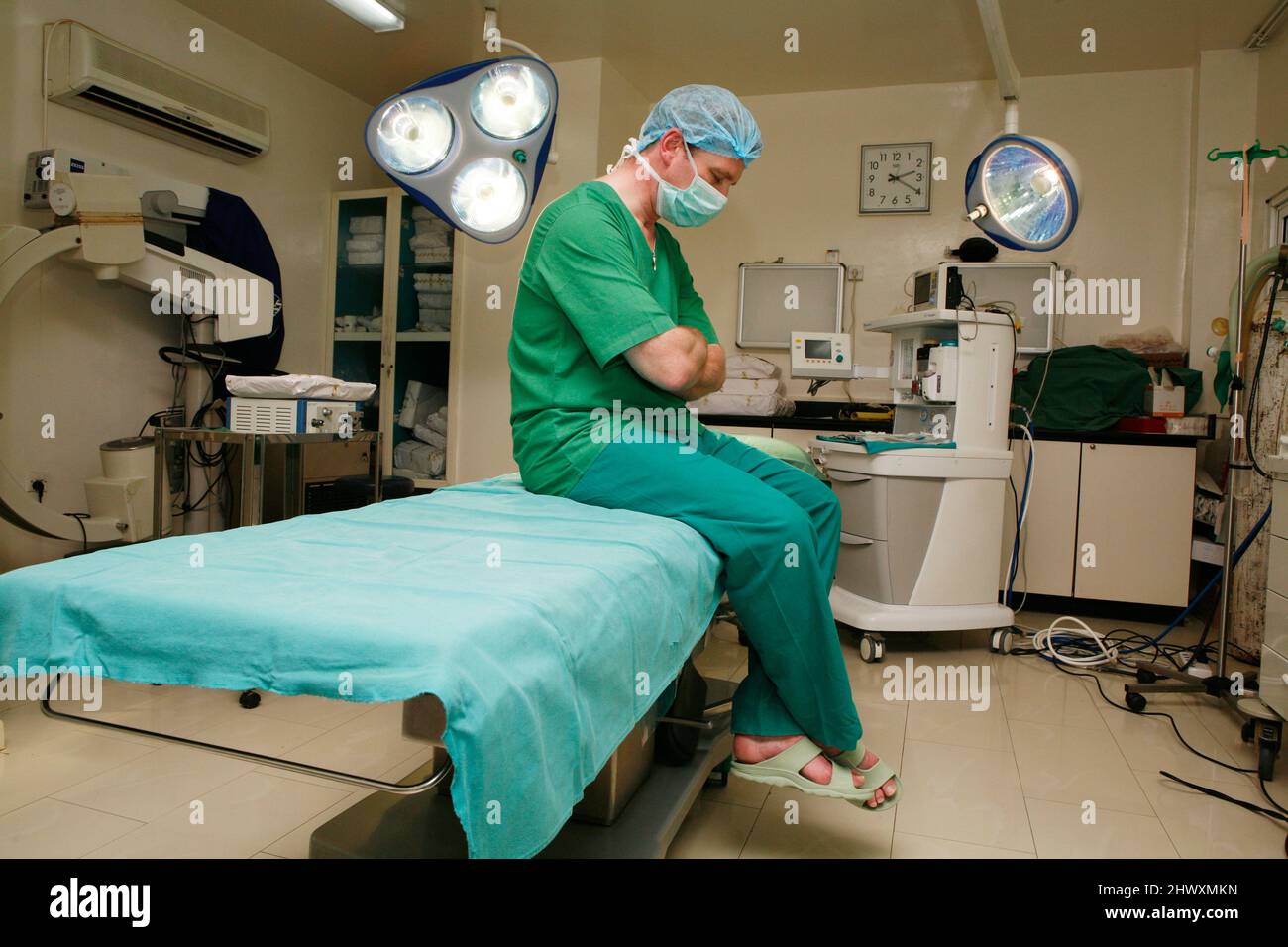 A tired surgeon sits and sleeps on an operating table. (MODEL RELEASED ...