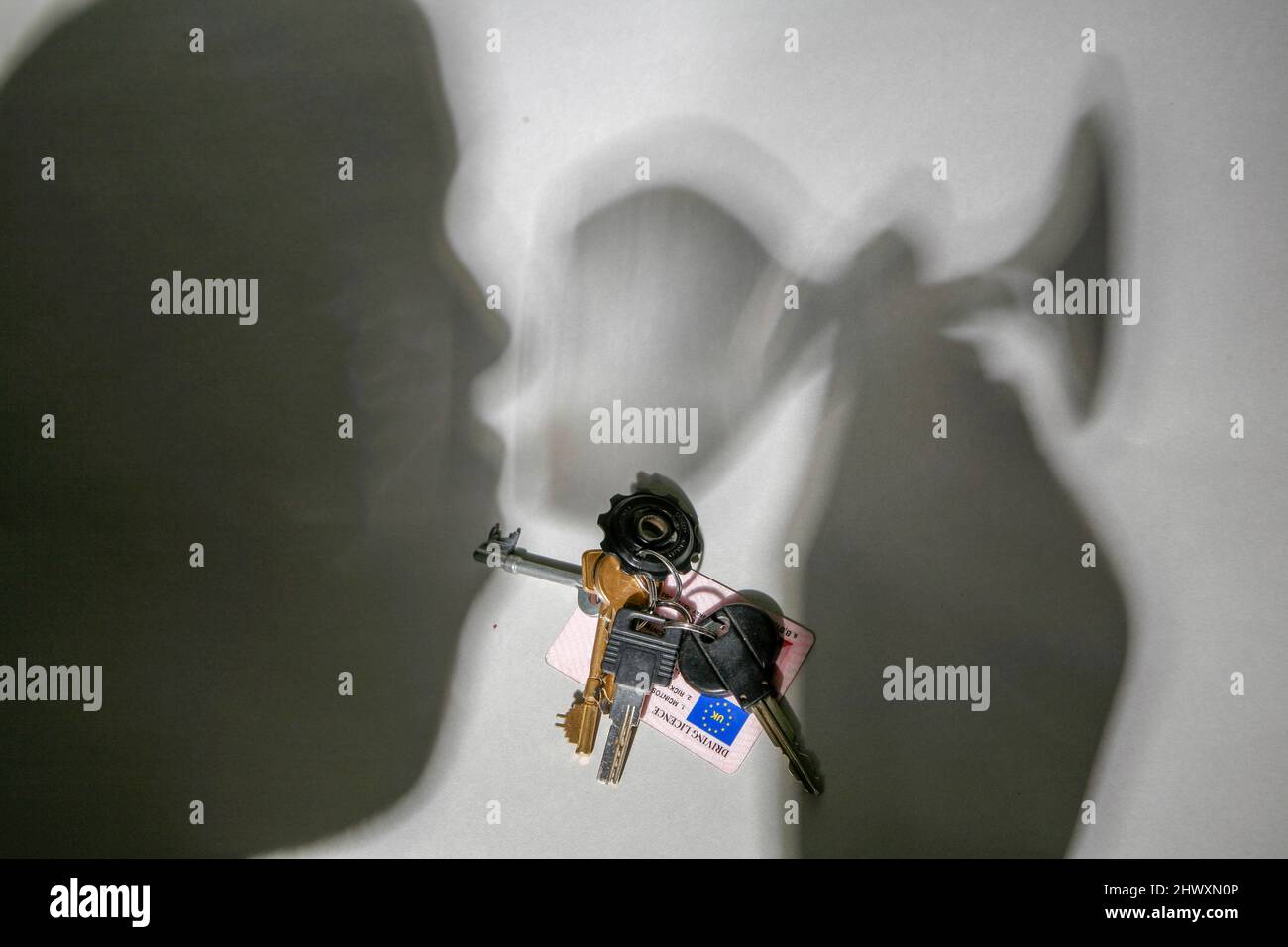 The shadow of a man drinking alcohol with his driving licence and car ...