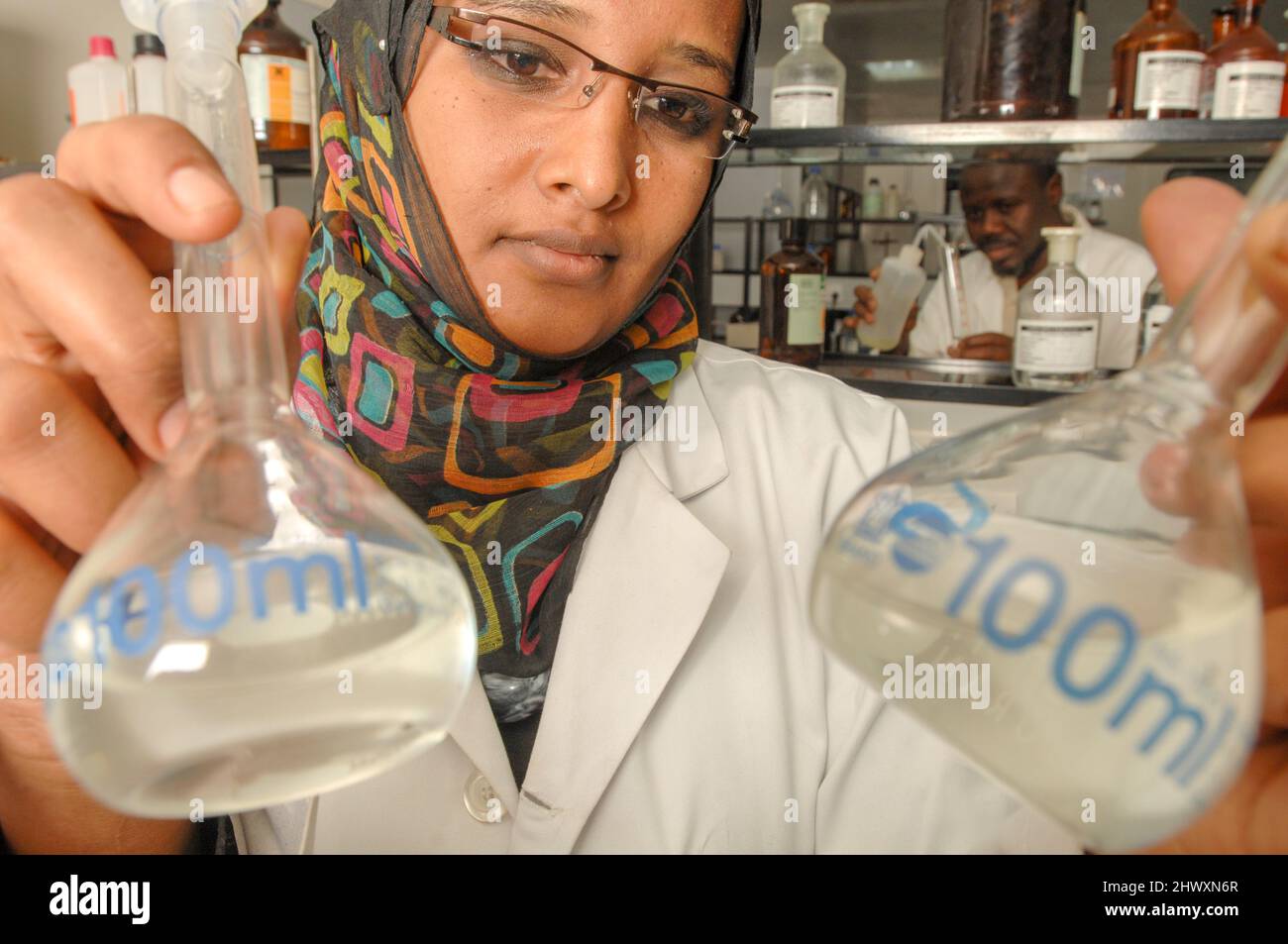 Laboratory assistant holding two 100ml volumetric flasks.(MODEL ...