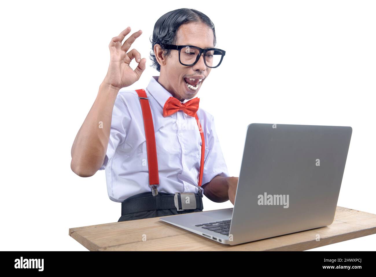 Asian nerd with an ugly face using laptop isolated over white ...