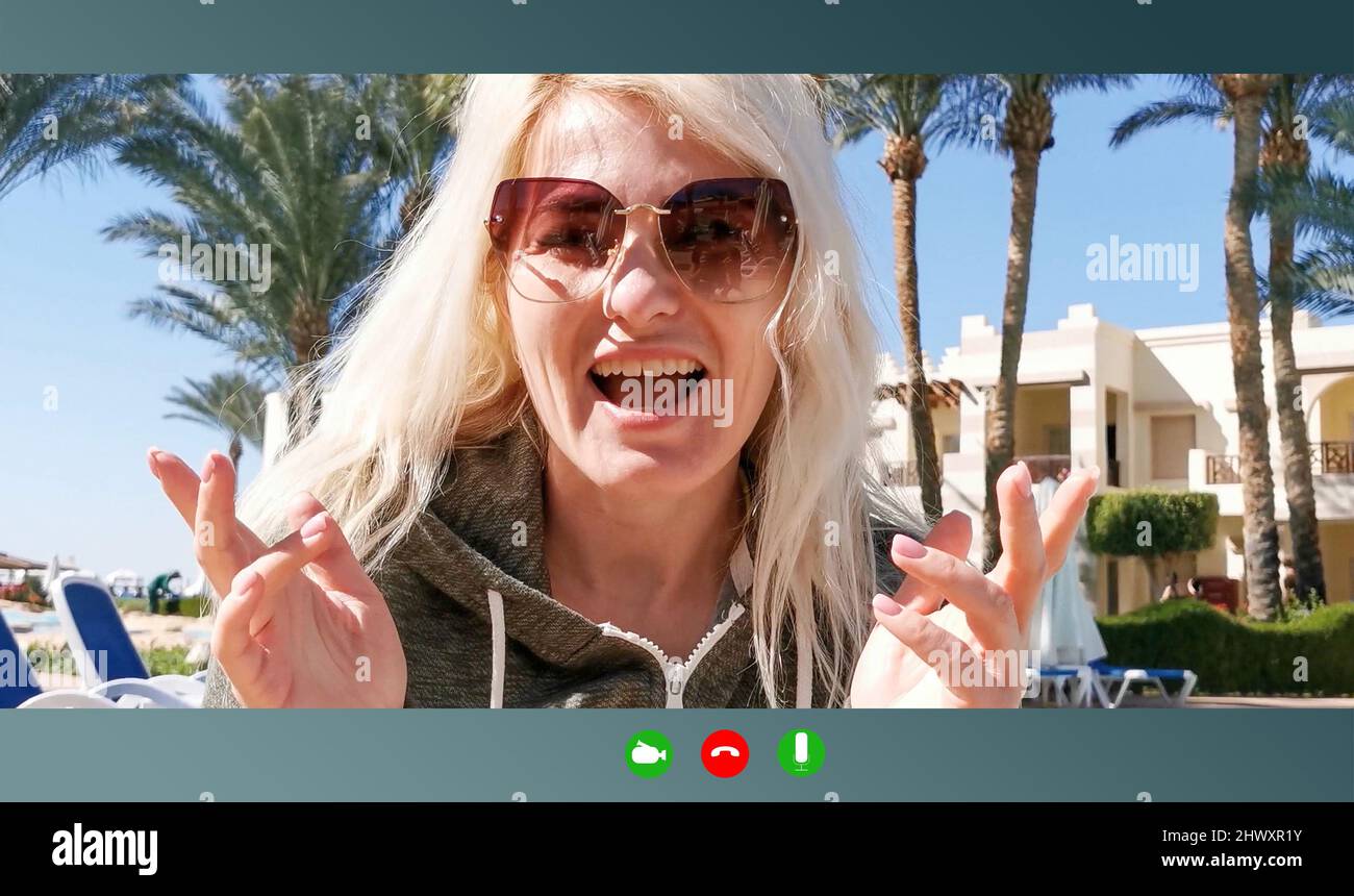 woman on the street among the palm trees talking by video link. Sunny ...