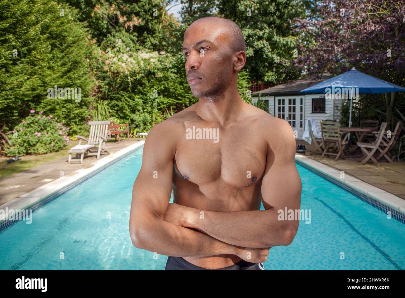 A young athletic looking male standing in front of a swimming pool ...