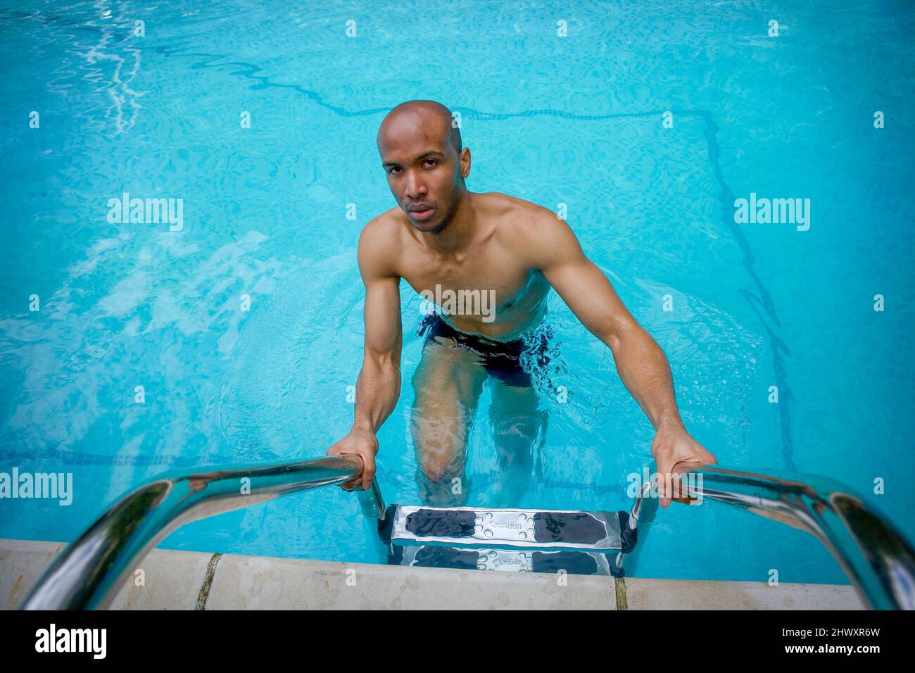 A young man climbing out of a swimming pool. (MODEL RELEASED Stock ...