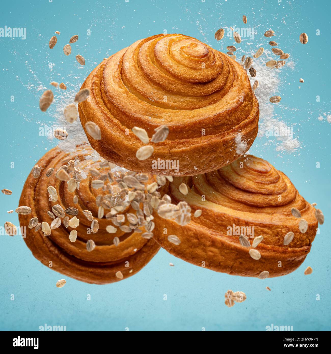 Cinnamon rolls buns with vanilla filling falling on blue background ...