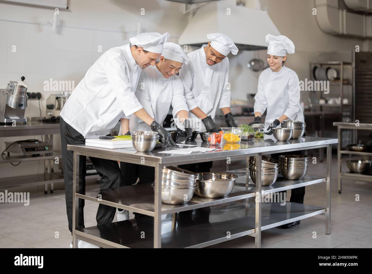 Multiracial team of cooks mixing ingredients for take away food in ...