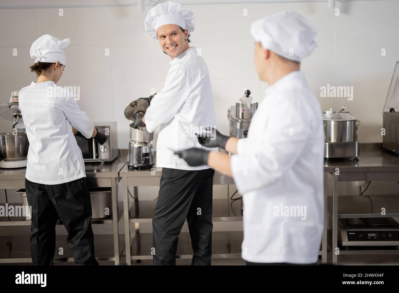 Multiracial well-dressed cooks cheering each other while cooking in ...
