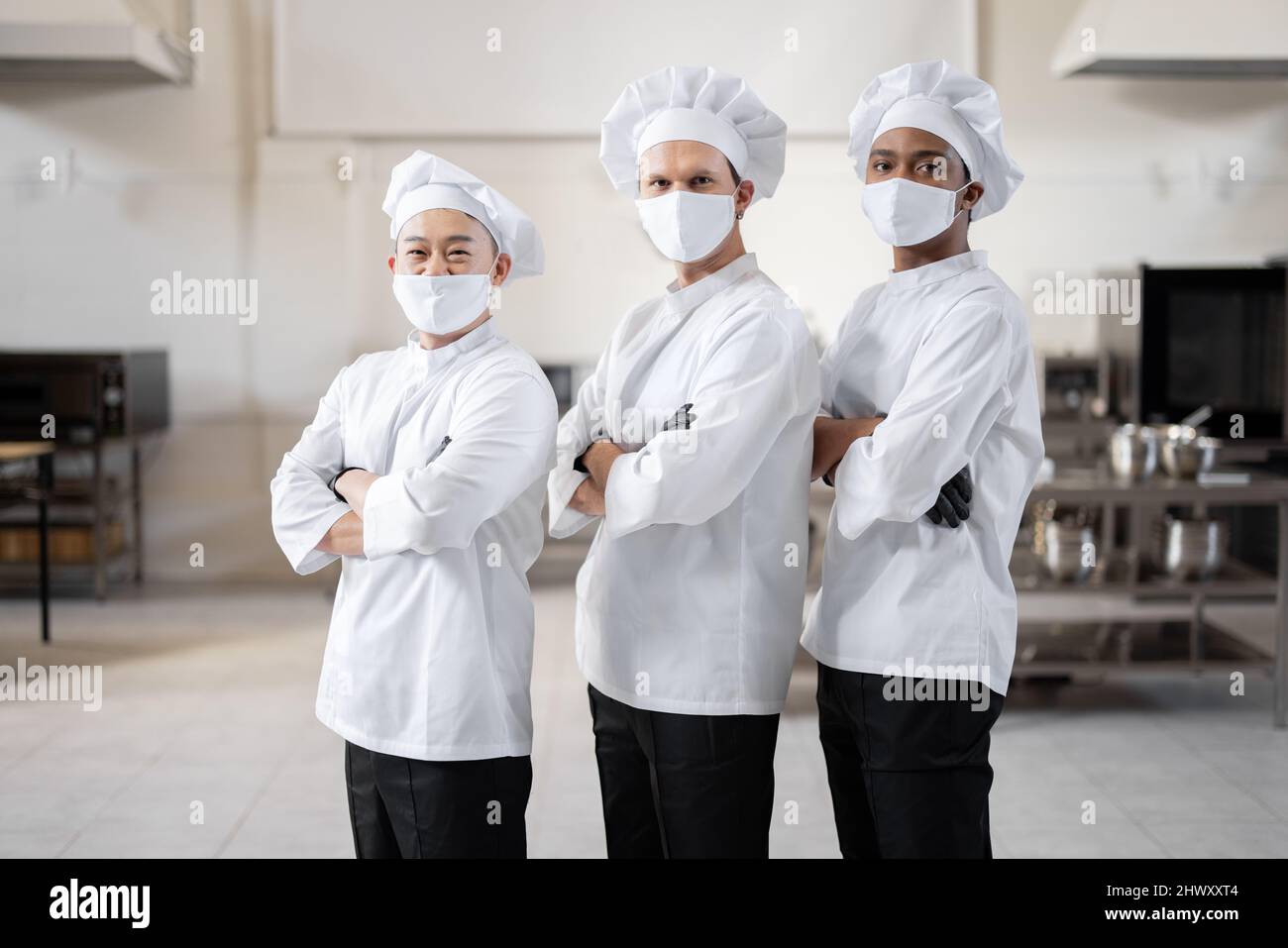 Portrait of multiracial team of three chefs standing together in the ...