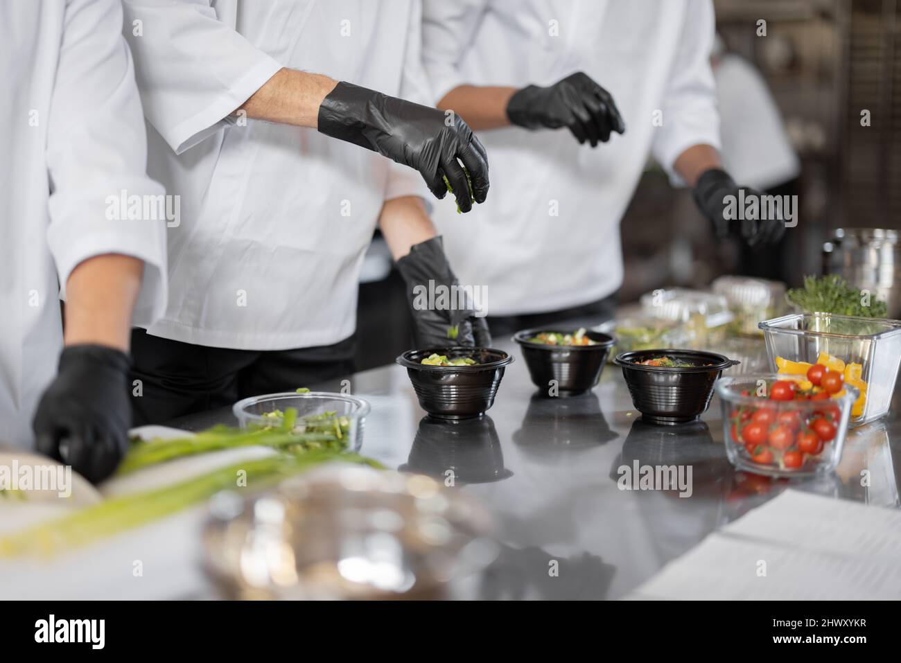 Chefs prepare takeaway food, mixing ingredients in disposable dish at ...