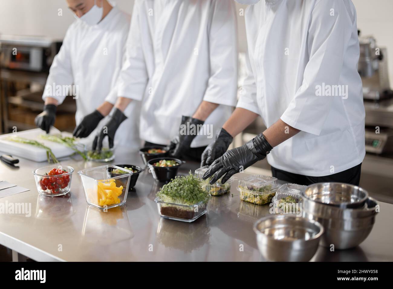 Chefs prepare takeaway food, mixing ingredients in disposable dish at ...