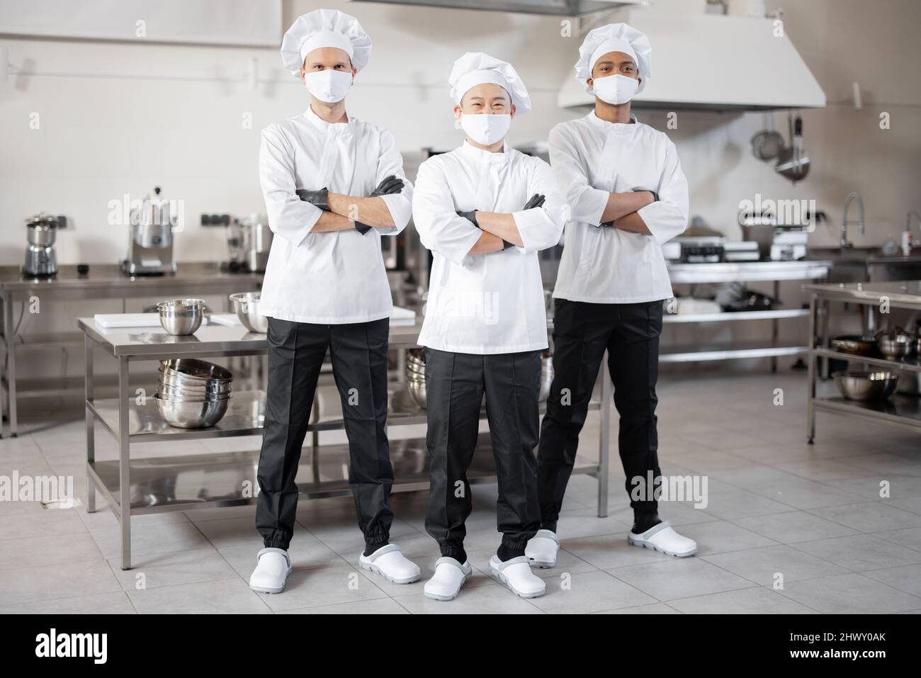 Full body portrait of multiracial team of three chefs standing together ...