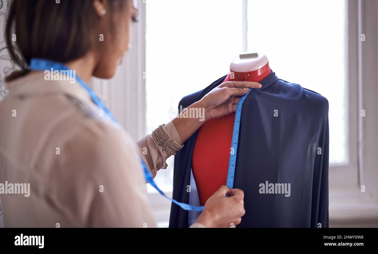 Perfecting her new design. A seamstress taking measurements for a ...