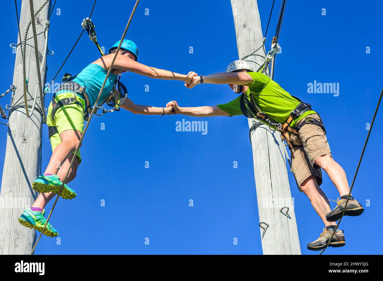 Two young people doing partner exercise in high ropes course Stock ...
