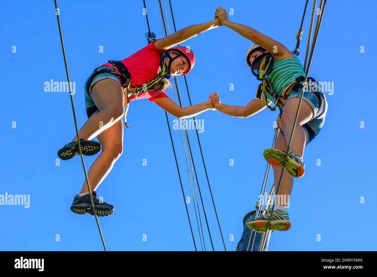 Two young women doing partner exercise in high ropes course Stock Photo ...
