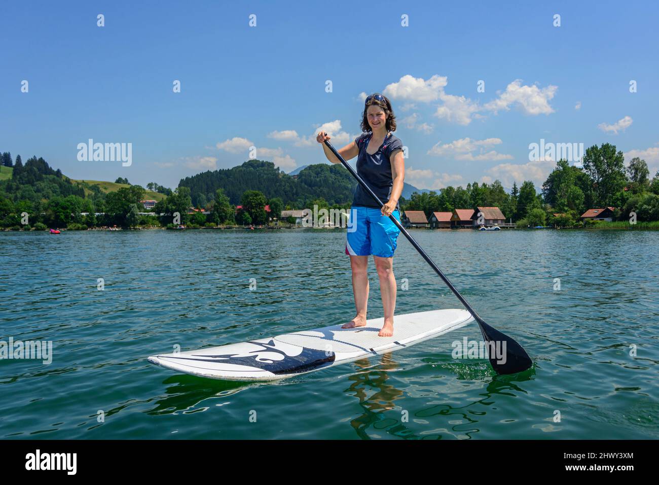 Sporty woman having fun on SUP board on the Alpsee in the Allgäu Stock ...