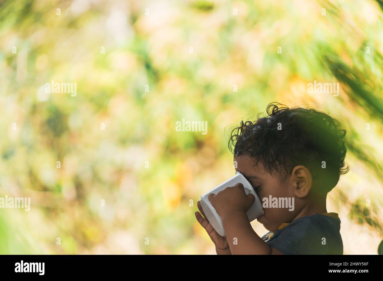 latin boy drinking coffee in a white cup, in a natural environment ...
