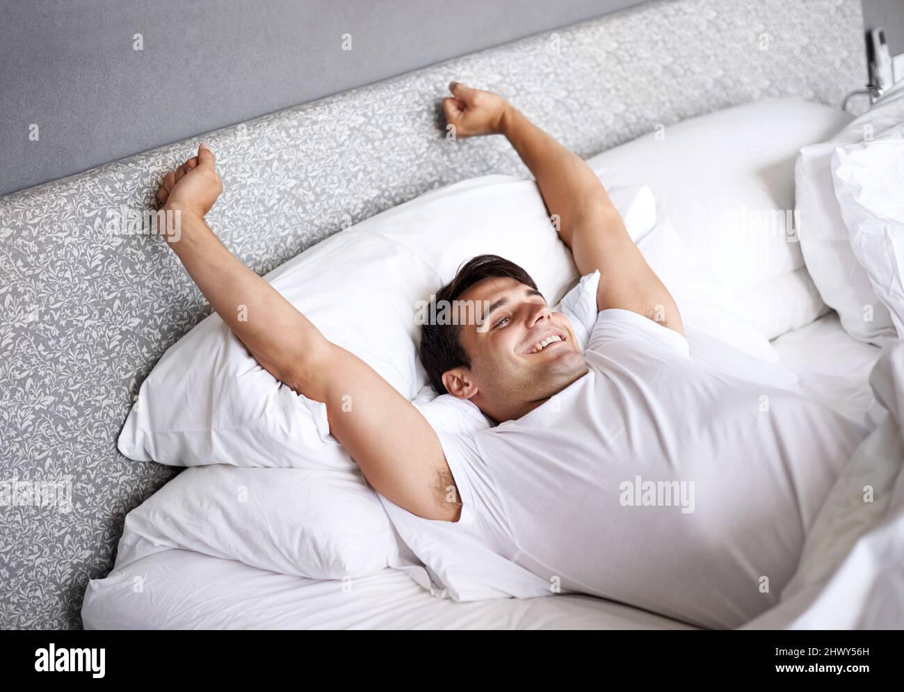 Time to wake up. Cropped shot of a young man stretching in bed while waking up Stock Photo - Alamy