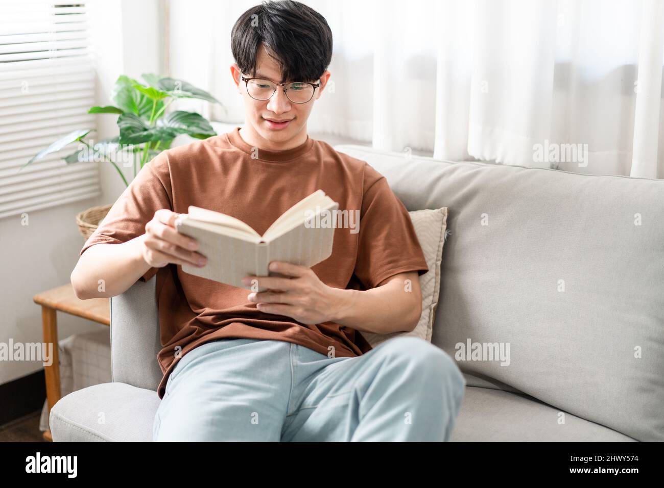 Technology Concept The male with his glasses sitting on the grey sofa ...