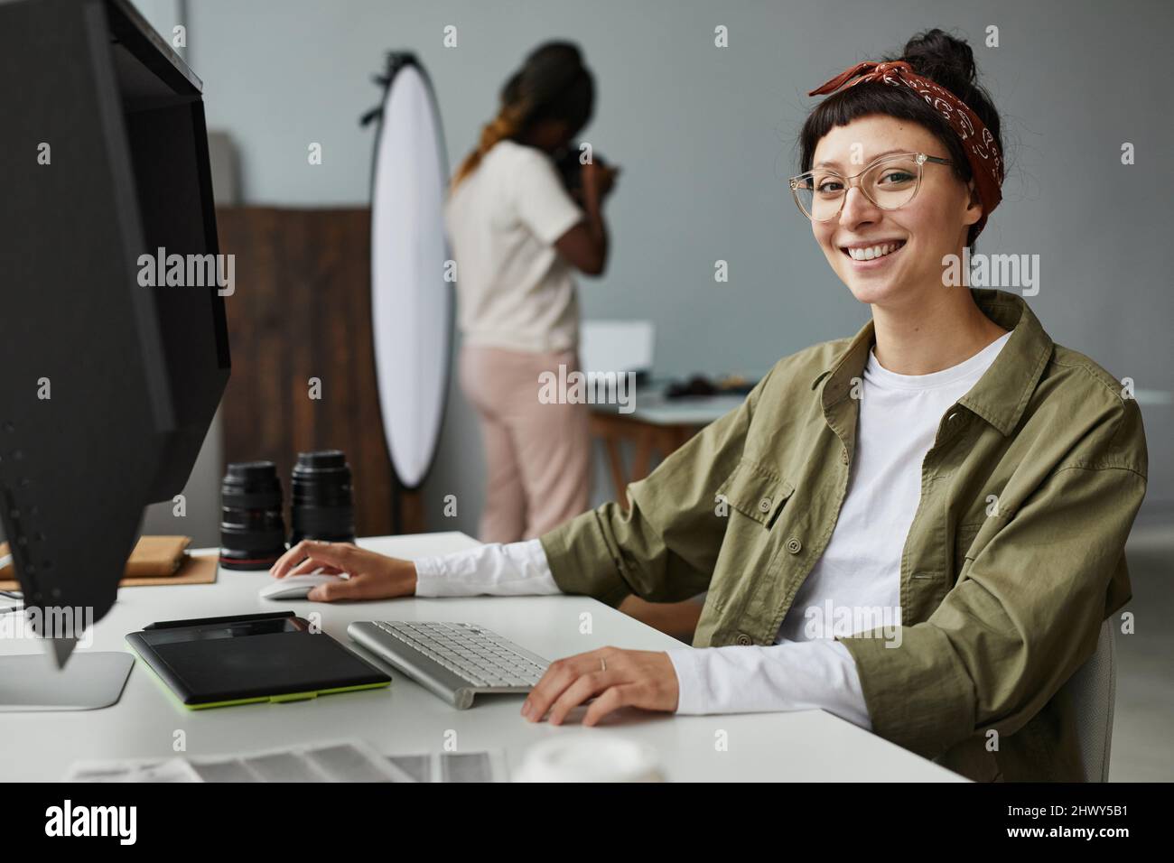 Portrait of smiling female photographer looking at camera while using ...