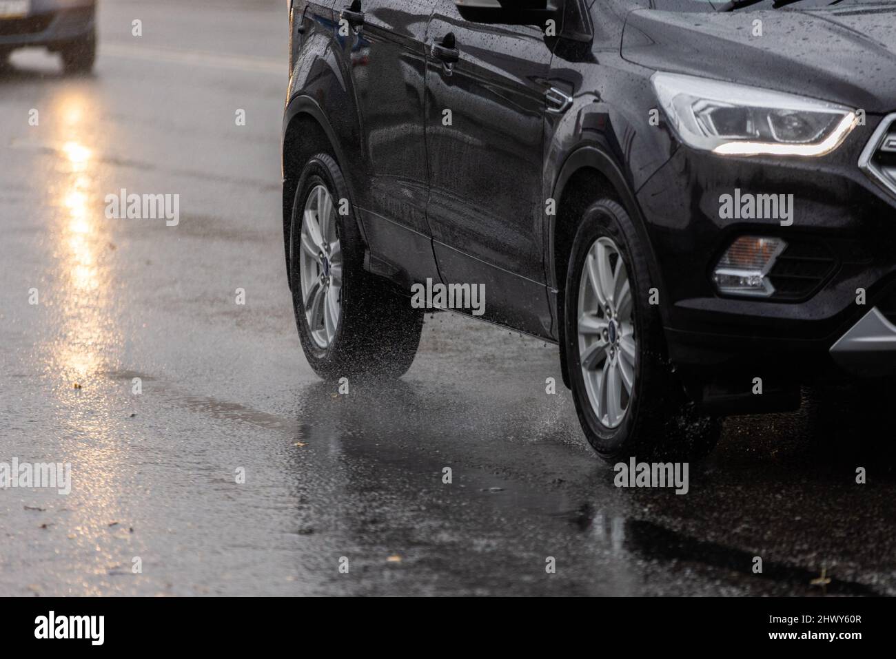rain water splash flow from wheels of black car moving fast in daylight ...