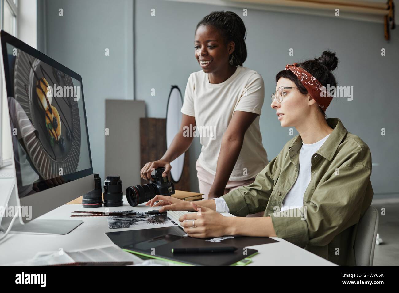 Portrait of two female photographers discussing images on computer ...