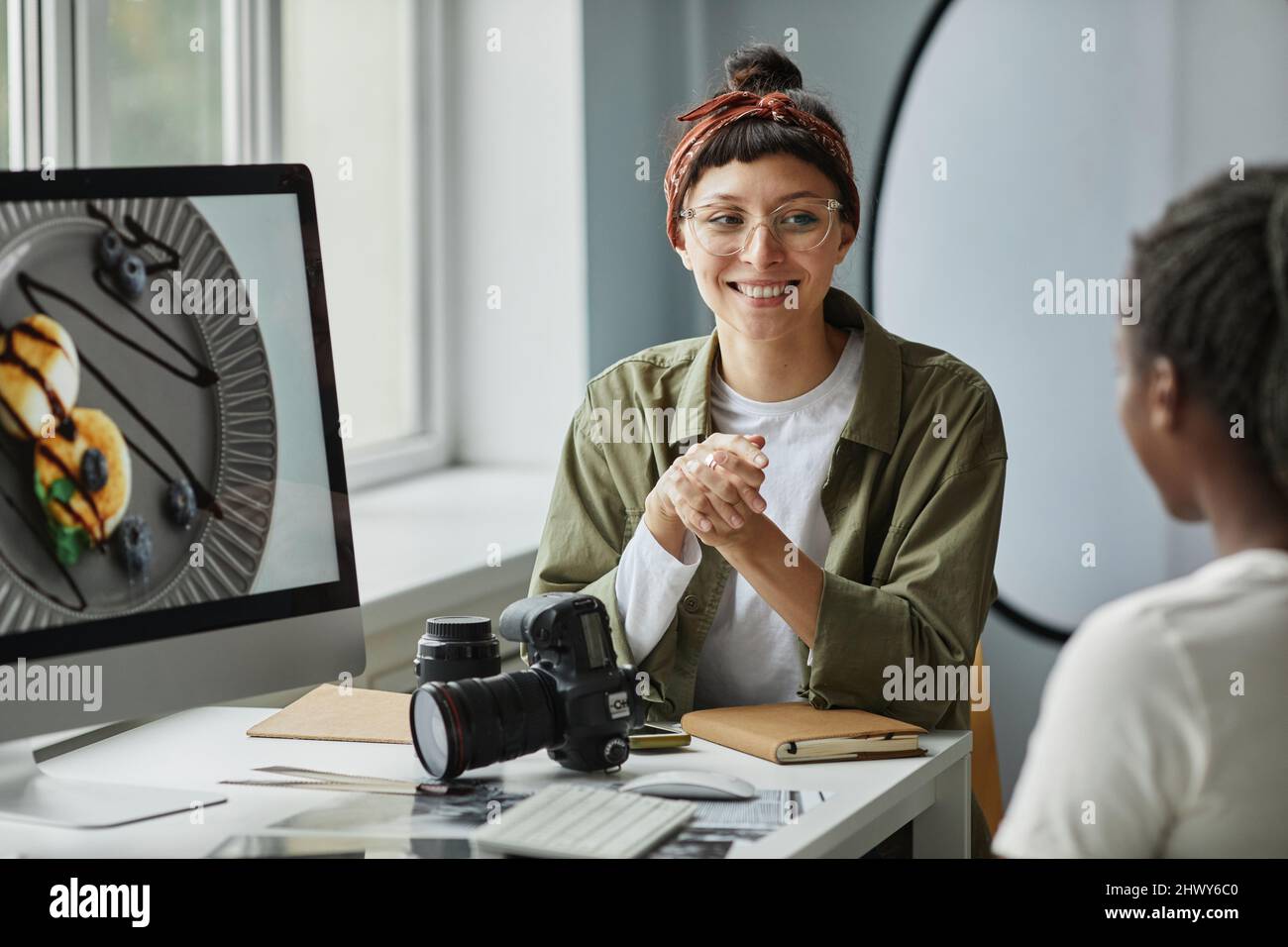 Portrait of smiling female photographer collaborating with colleague or ...