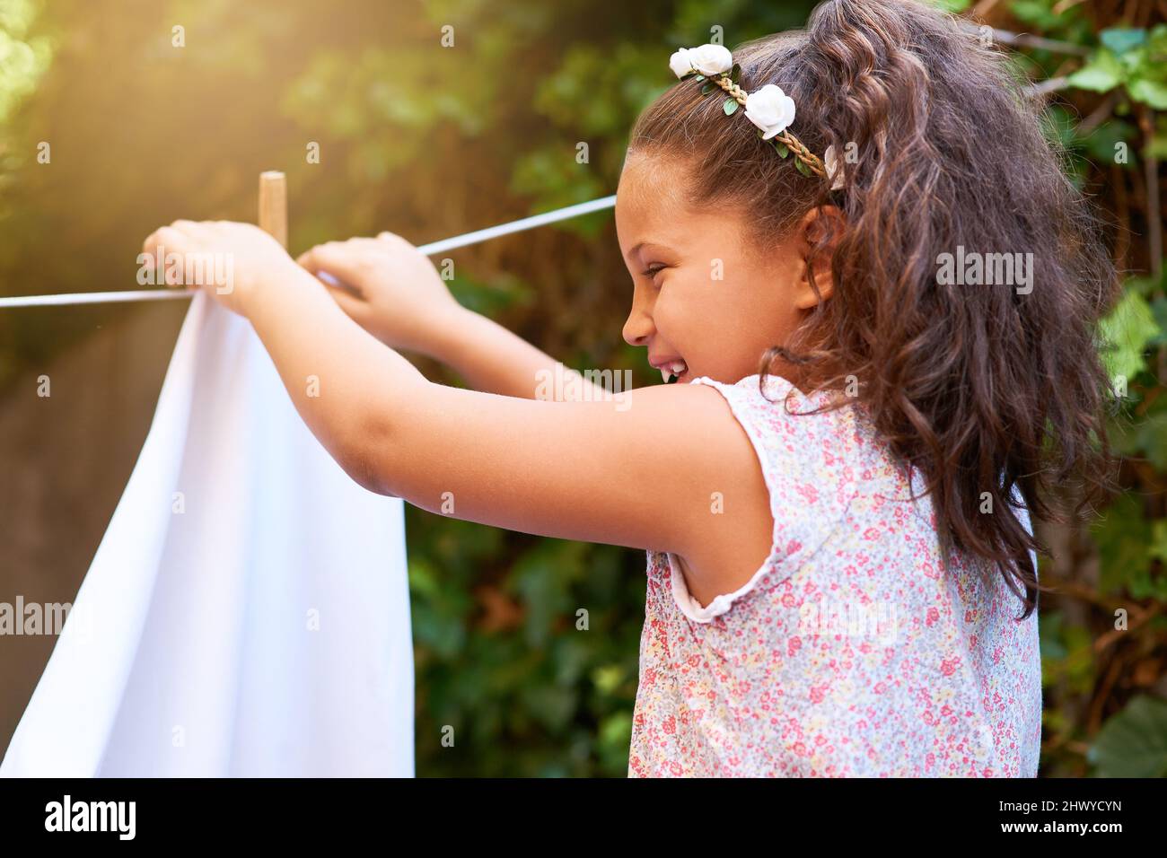 Shes full of laughter. Shot of a young girl hanging up laundry on a ...