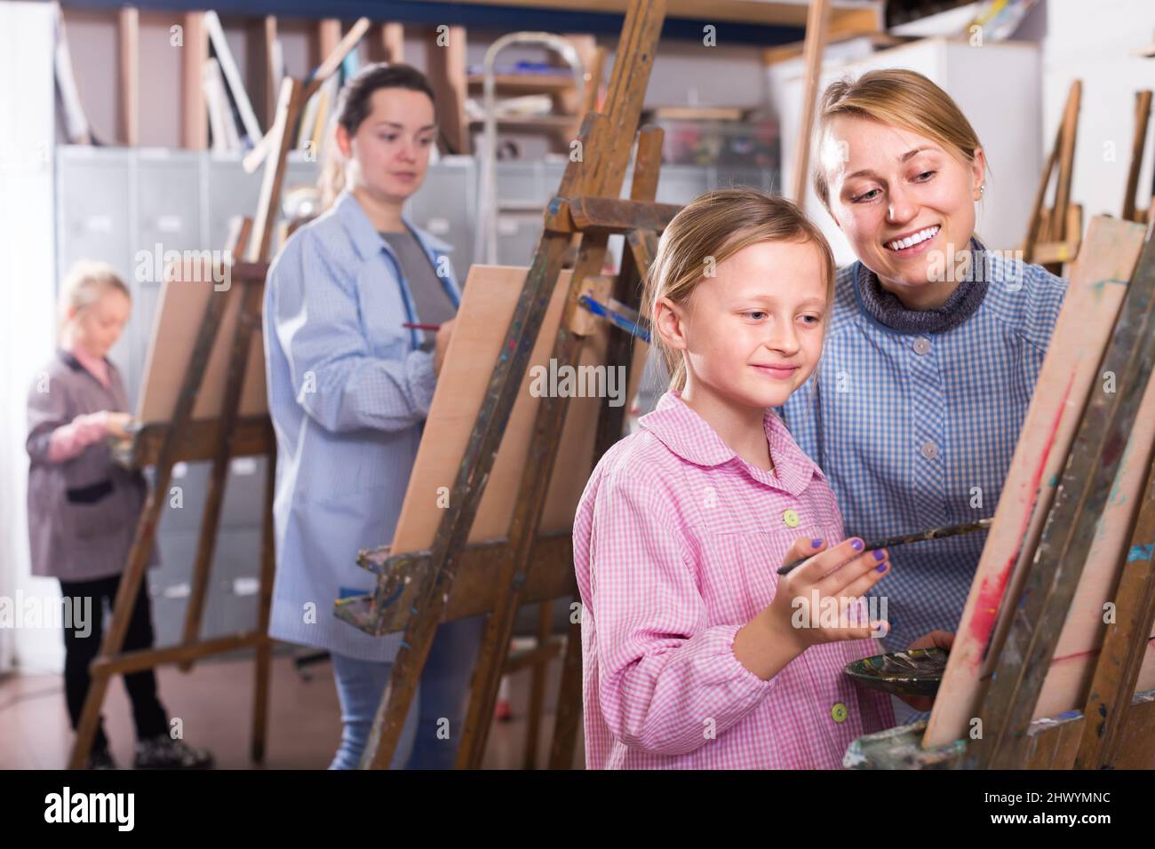Smiling woman assistance girl during painting class Stock Photo - Alamy