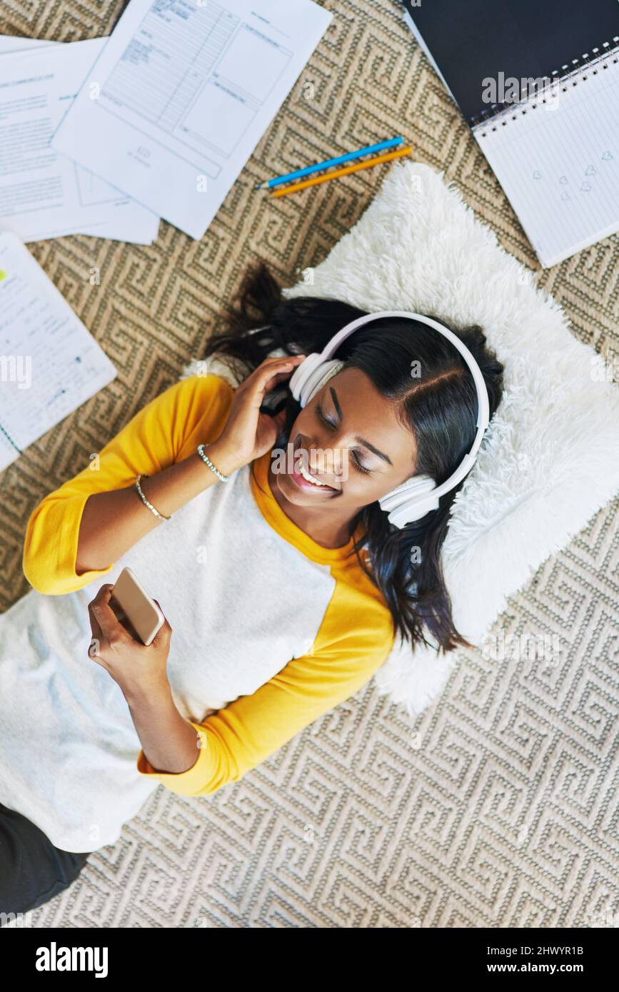 Selecting the perfect music to study to. High angle shot of a young ...