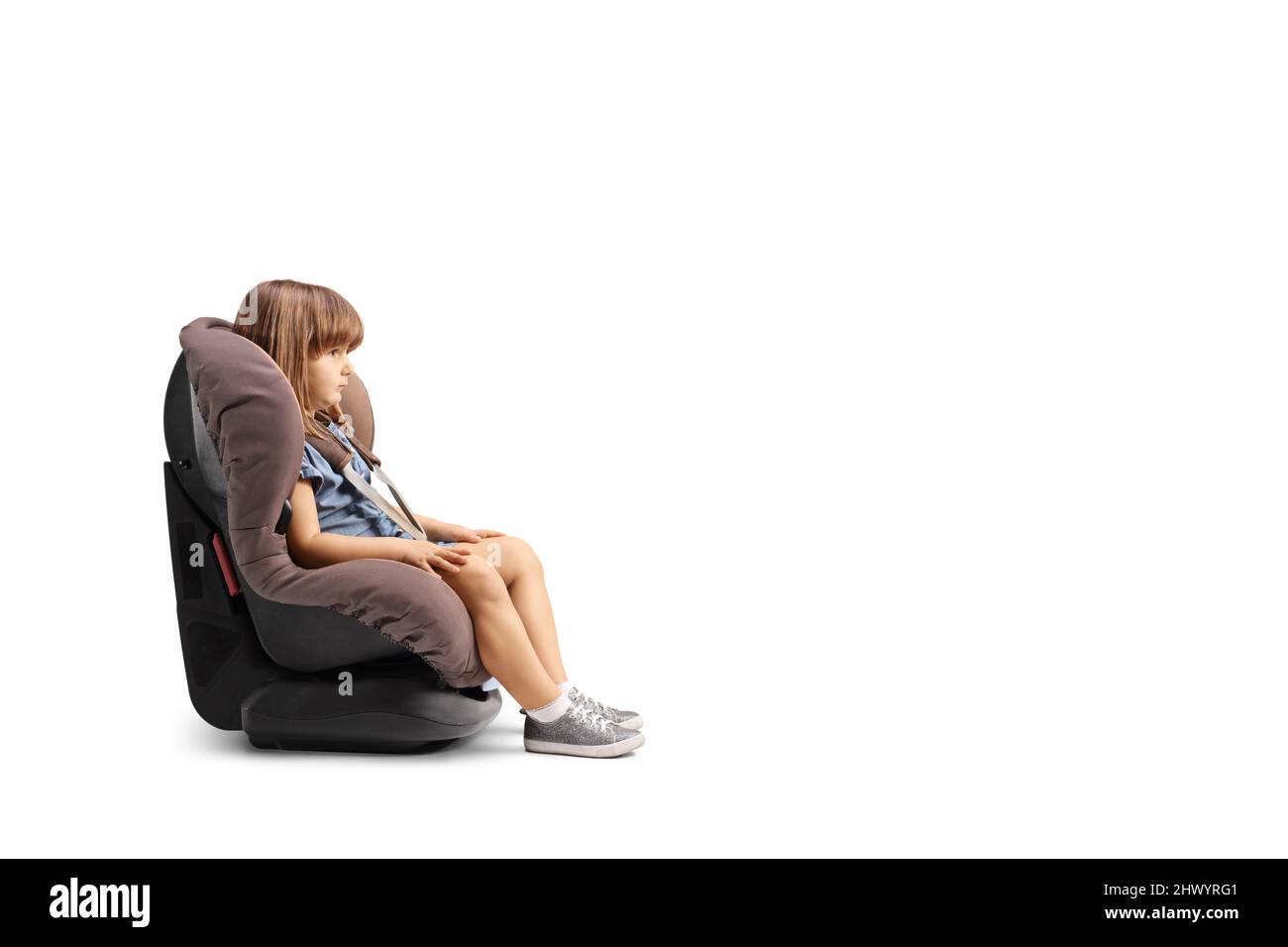 Profile shot of a little girl sitting in a car seat isolated on white ...