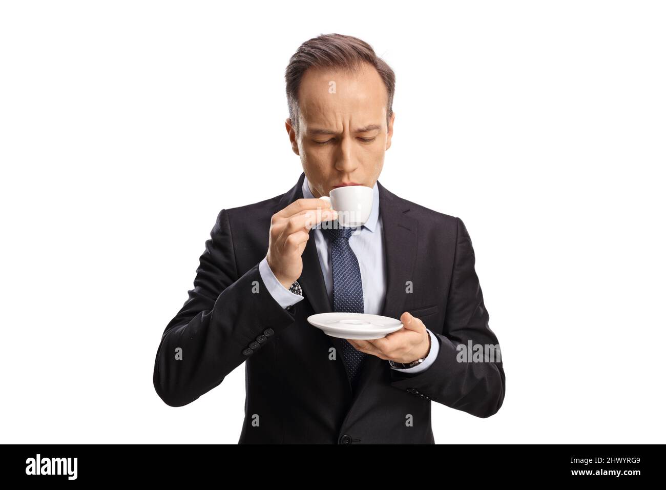 Businessman taking a sip of espresso coffee isolated on white ...