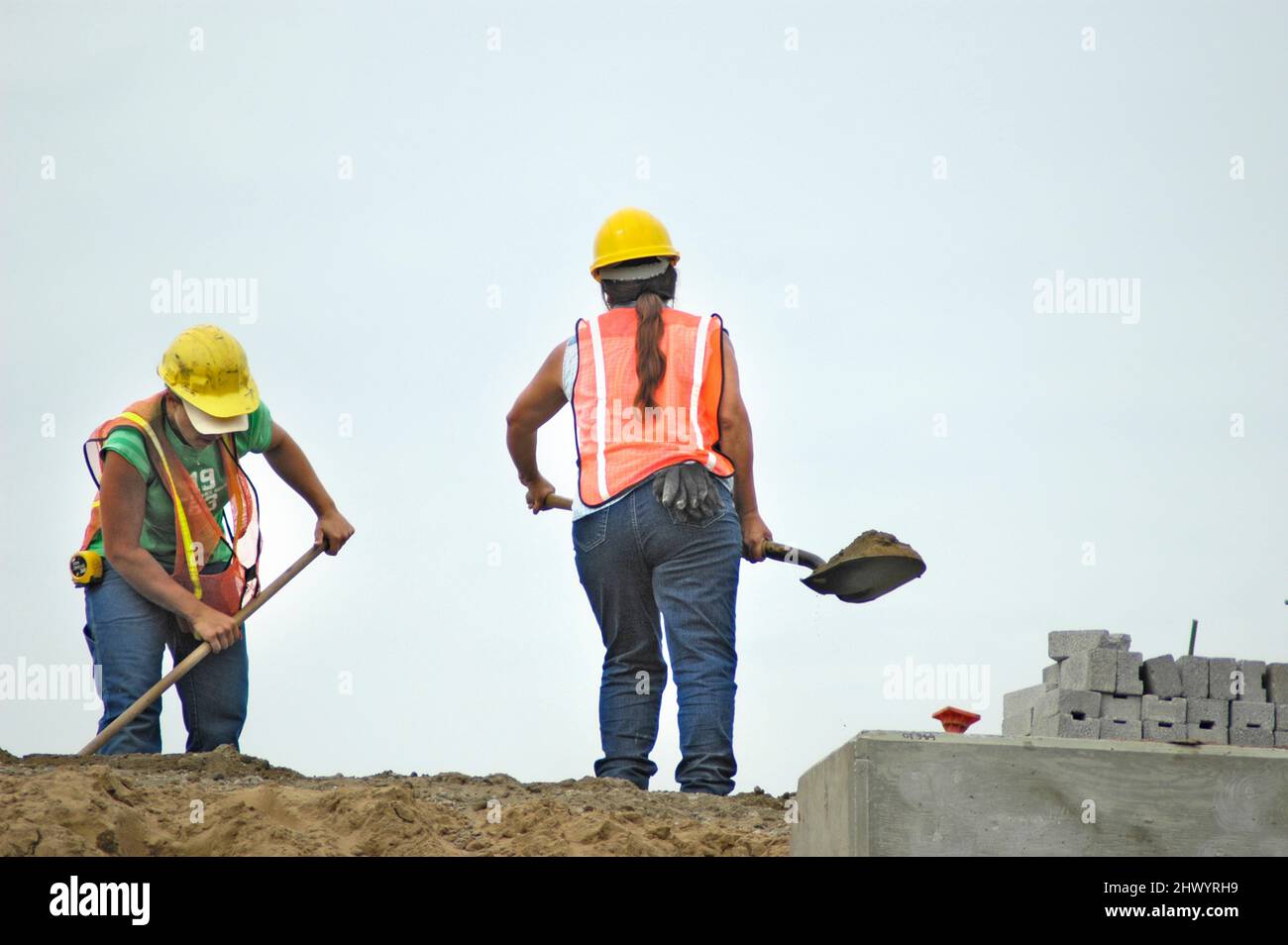 Highway construction site with women working hard labor with shovels ...