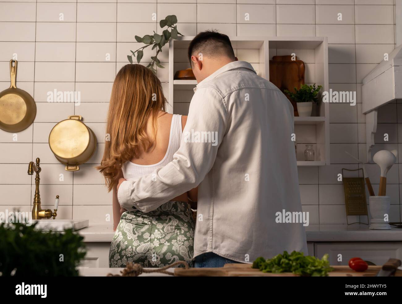 Back view of couple cooking in modern white kitchen in scandi style ...