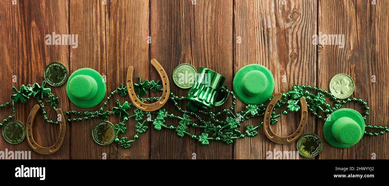 St Patricks Day border of shamrocks beads and coins over a rustic wood ...