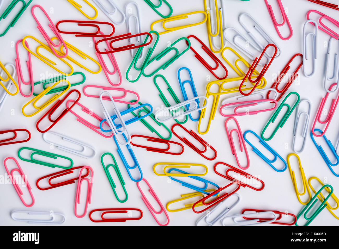 Cheerful background of colored paper clips on a white background ...