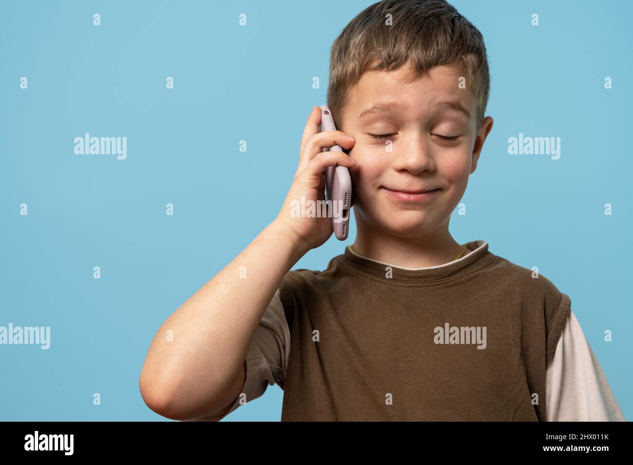 funny Caucasian boy is talking on the phone with his eyes closed with ...