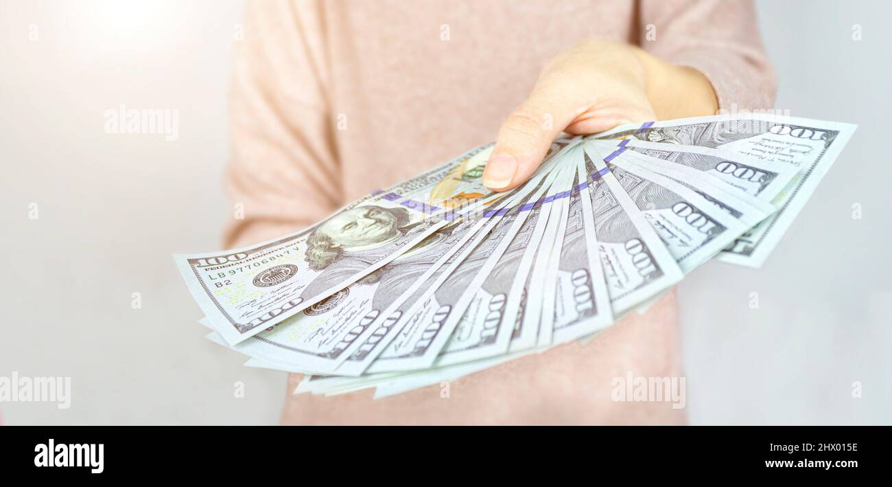 Woman holding fanned out money. Close up of hand giving money dollar ...
