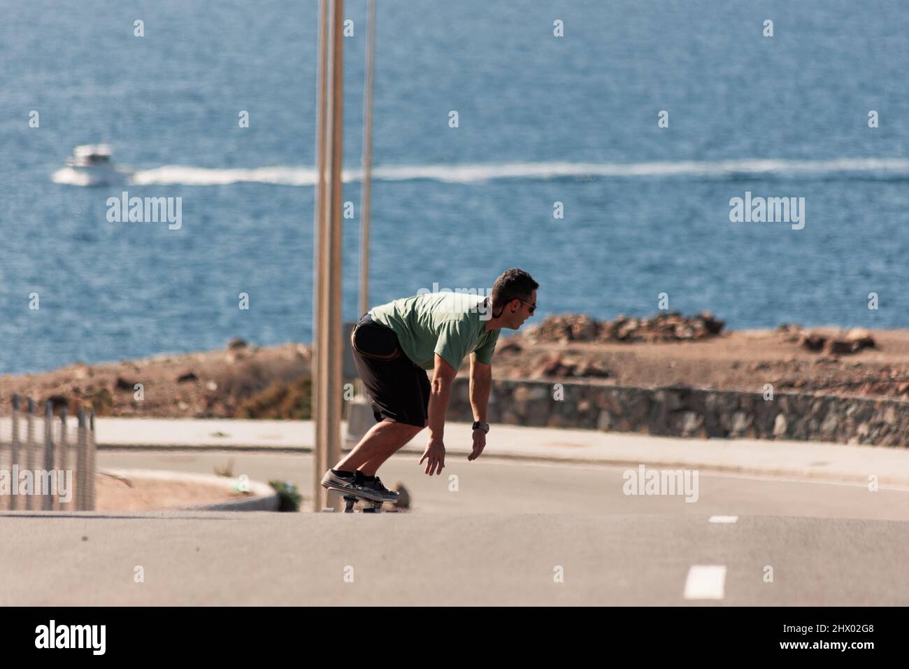 A man playing figure skating on a rural road in the sun on a bright day ...