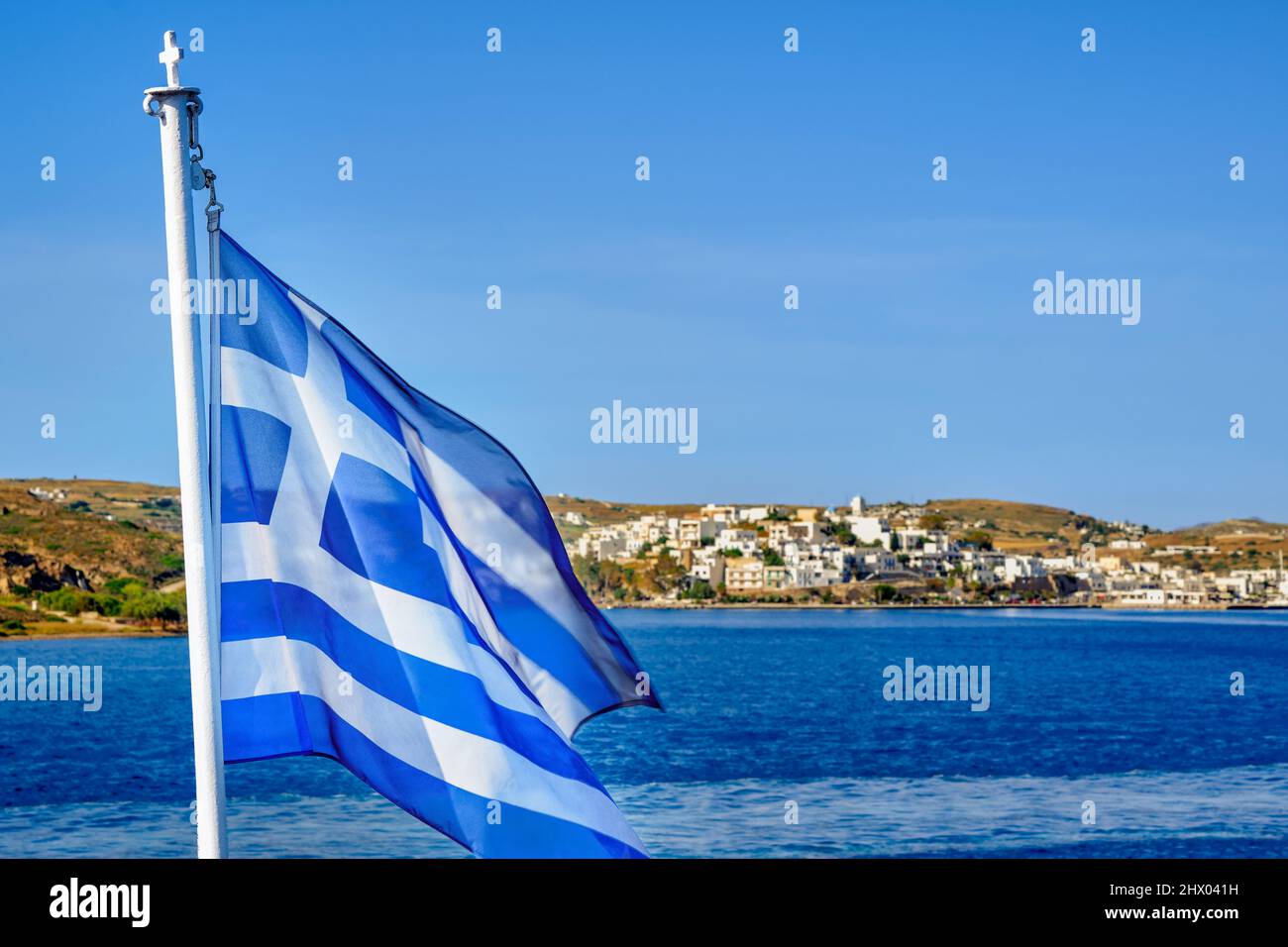 Greek flag waving at blurred typical Greek island landscape background ...