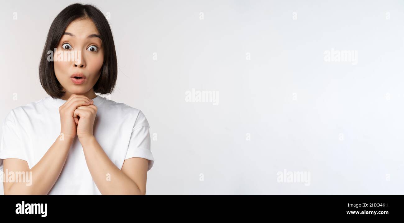 Close up portrait of asian brunette woman looking amazed, say wow ...
