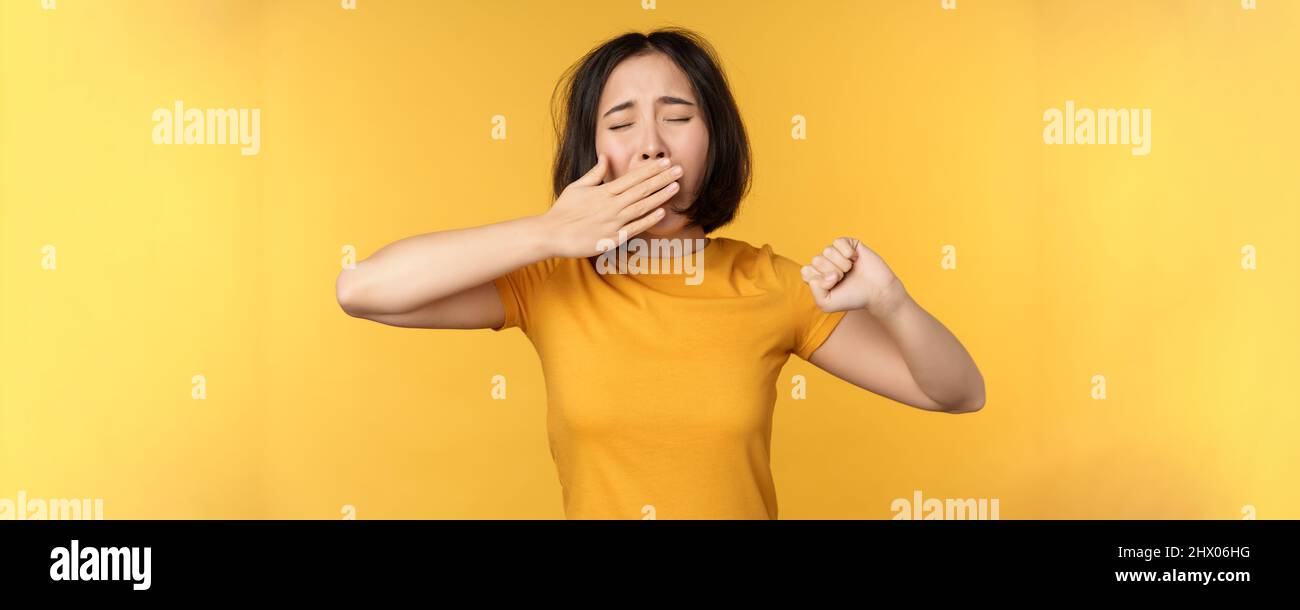 Image of young asian girl student, yawning, feeling tired, standing ...